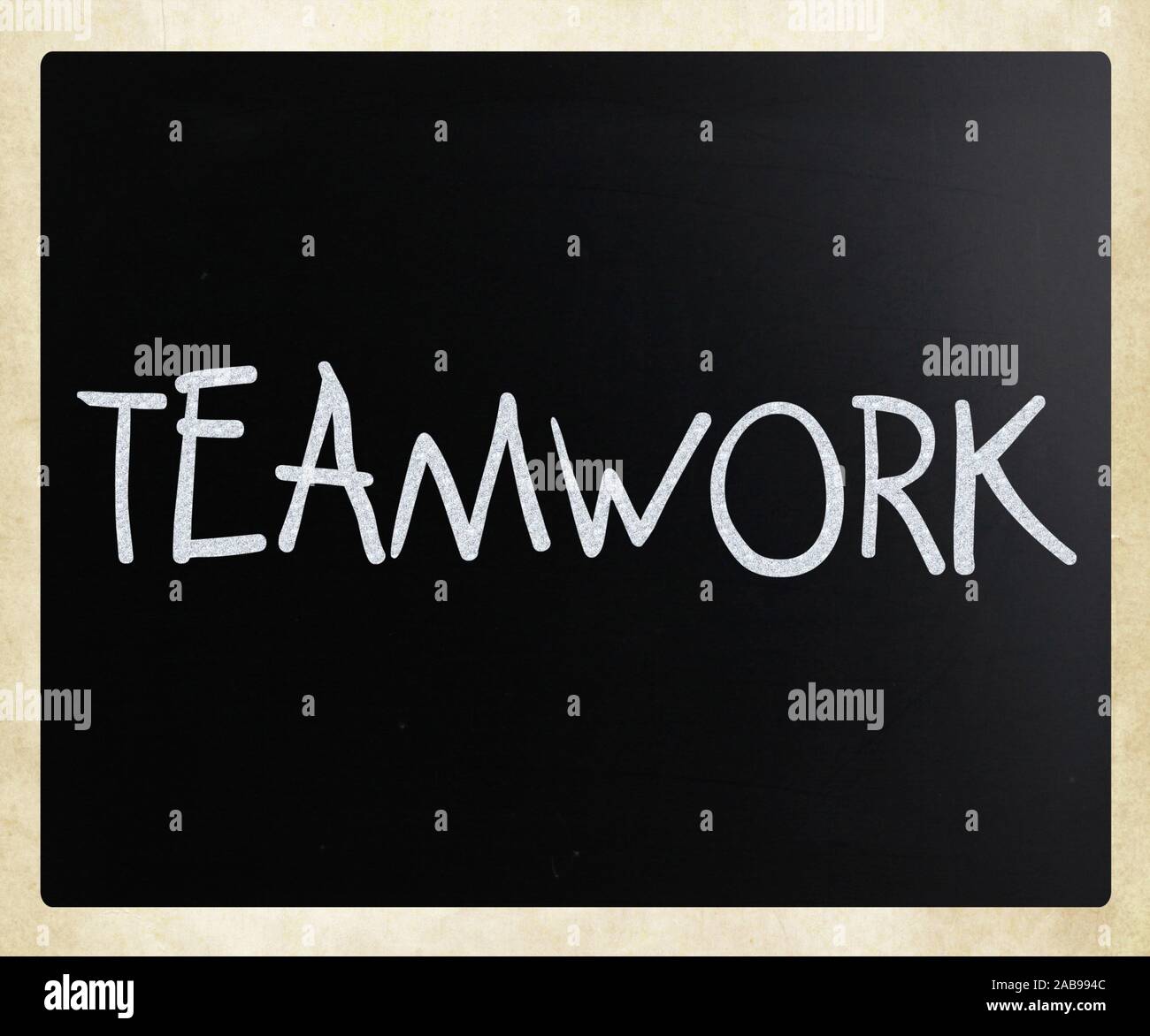 The word ""Teamwork"" handwritten with white chalk on a blackboard ...