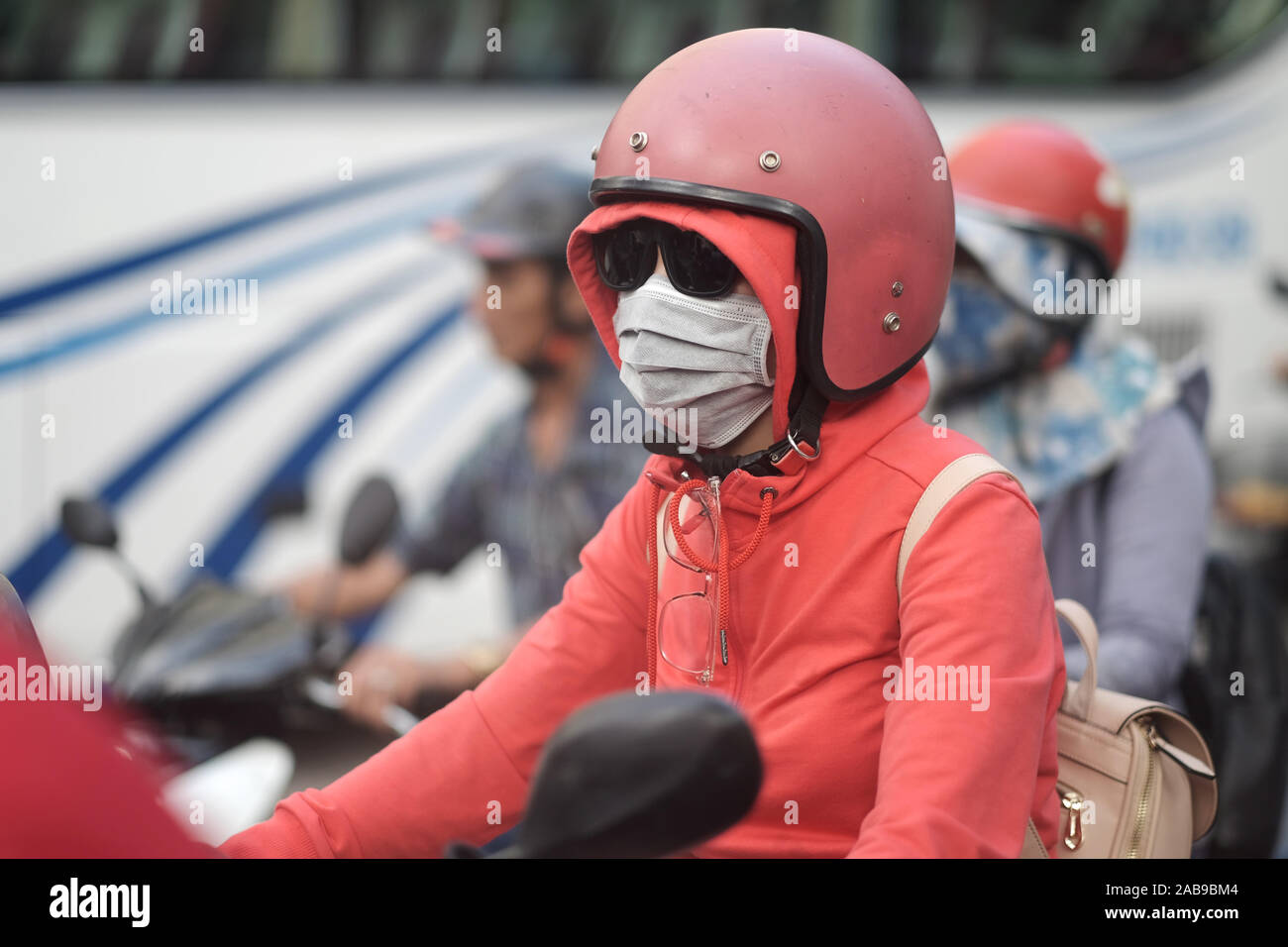A woman behind the wheel of a motor scooter in a hood and a protective ...