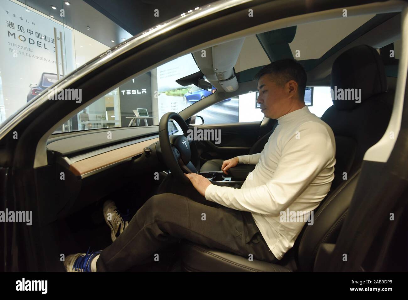 A man tries out a Chinese-manufactured Tesla Model 3 electric car on ...