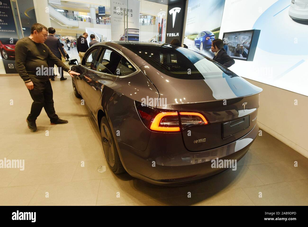 People look at a Chinese-manufactured Tesla Model 3 electric car on ...
