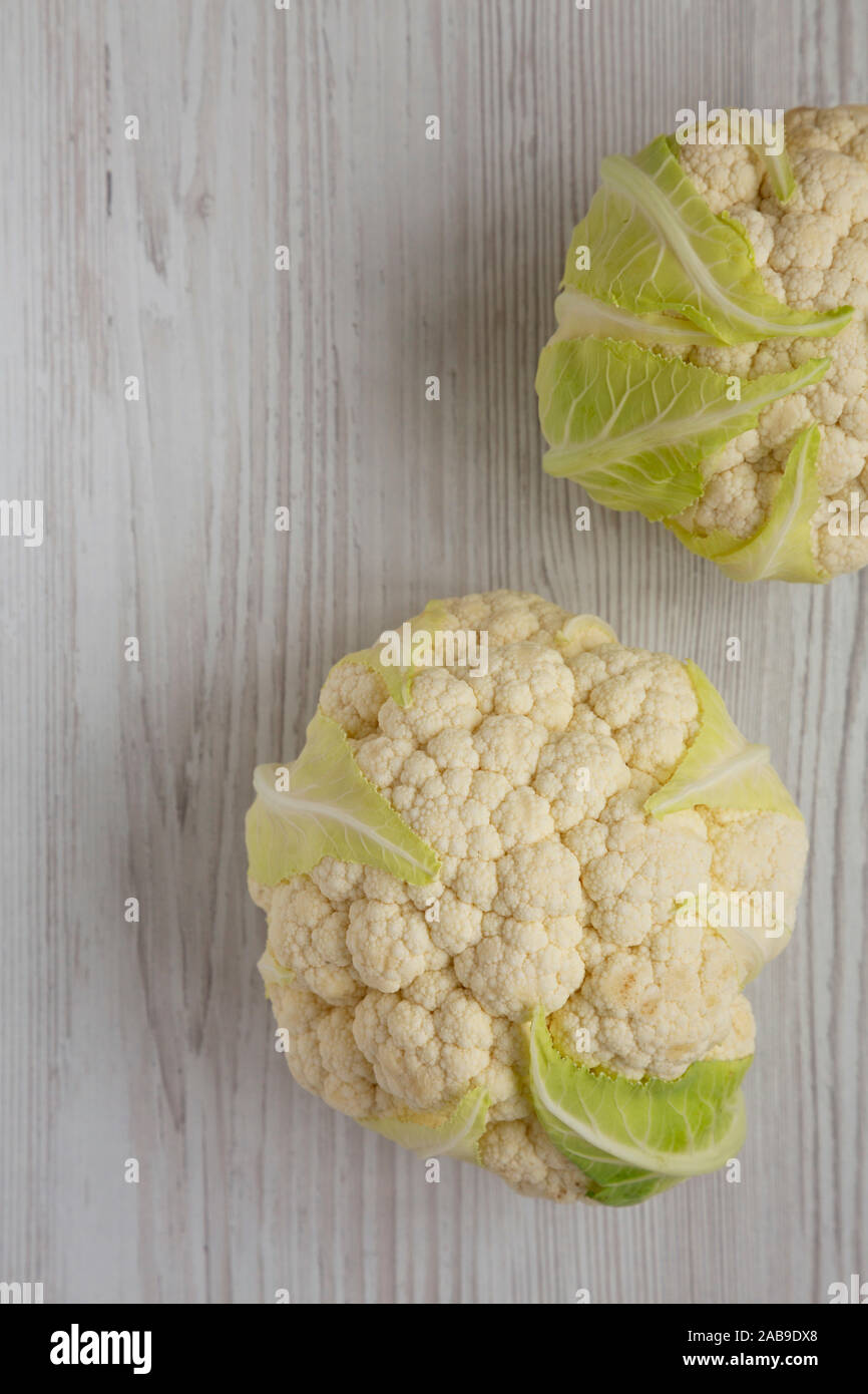 Raw Cauliflower Head on a white wooden surface, top view. From above ...
