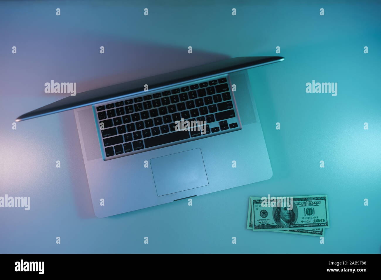 Beautiful silver laptop and cash dollars banknote in the color light on ...