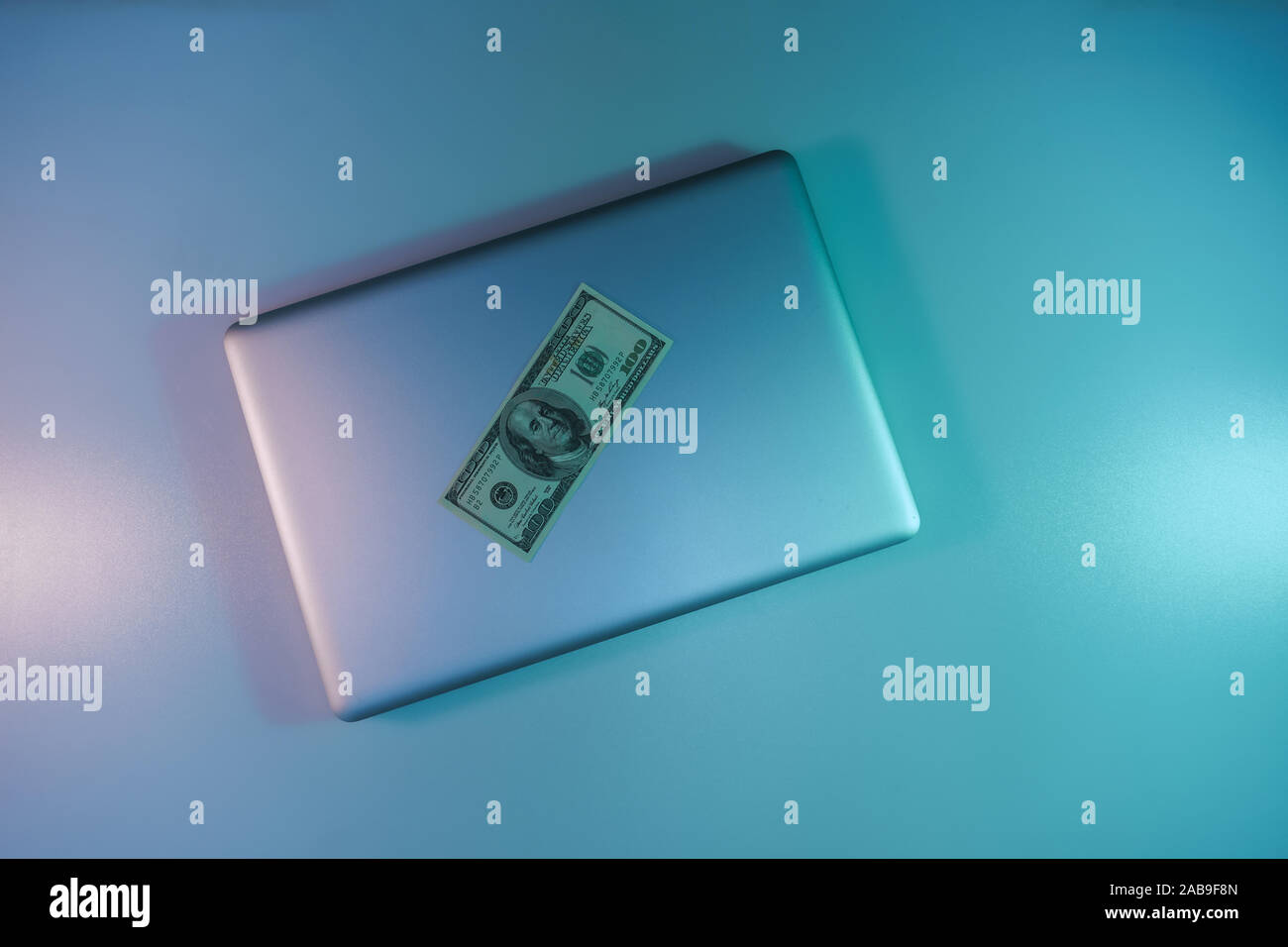 Beautiful silver laptop and cash dollars banknote in the color light on ...