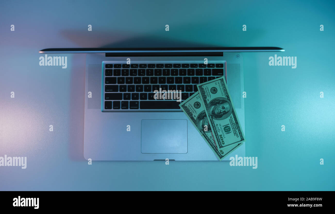 Beautiful silver laptop and cash dollars banknote in the color light on ...