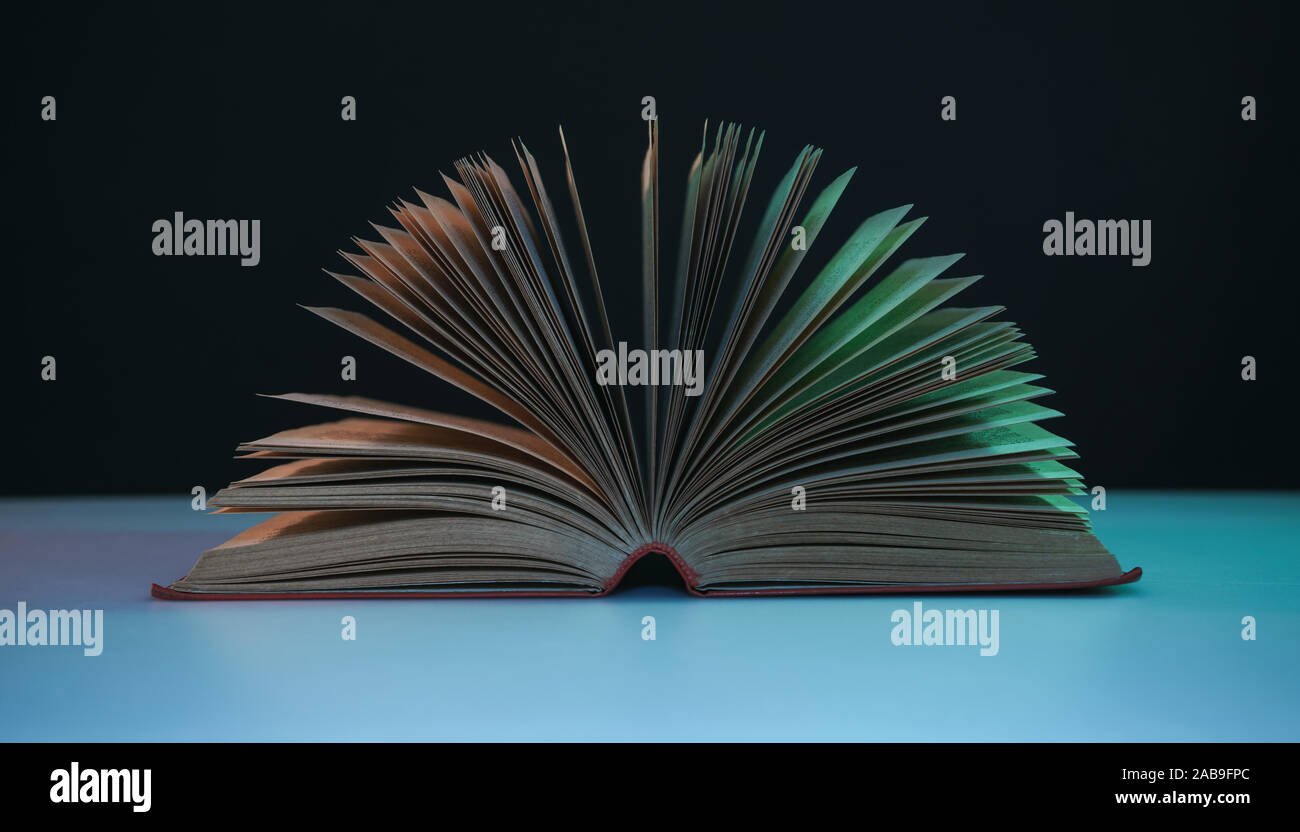 Beautiful open book pages in the color neon light on a table and night ...