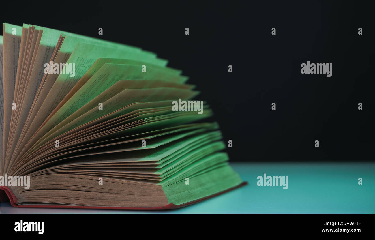 Beautiful open book pages in the color neon light on a table and night ...