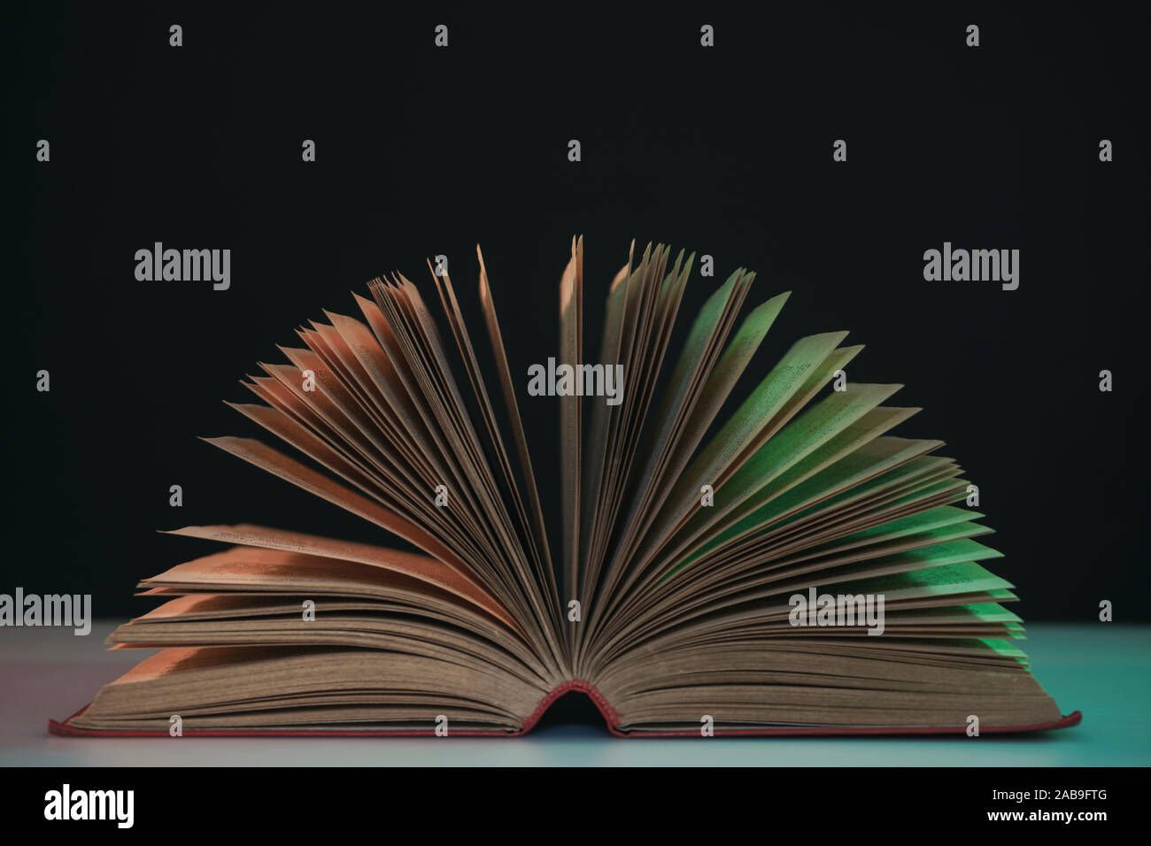 Beautiful open book pages in the color neon light on a table and night ...