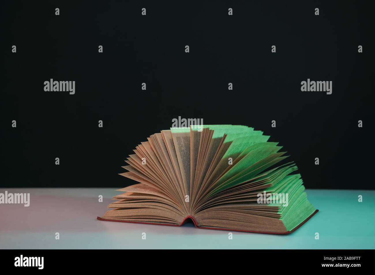 Beautiful open book pages in the color neon light on a table and night ...