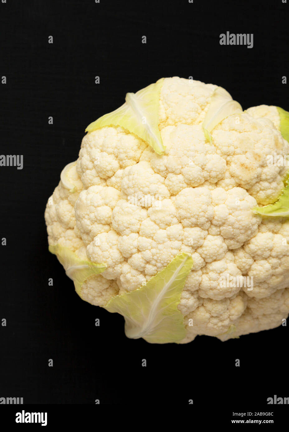 Raw Cauliflower Head on a black surface, overhead view. Flat lay, top ...