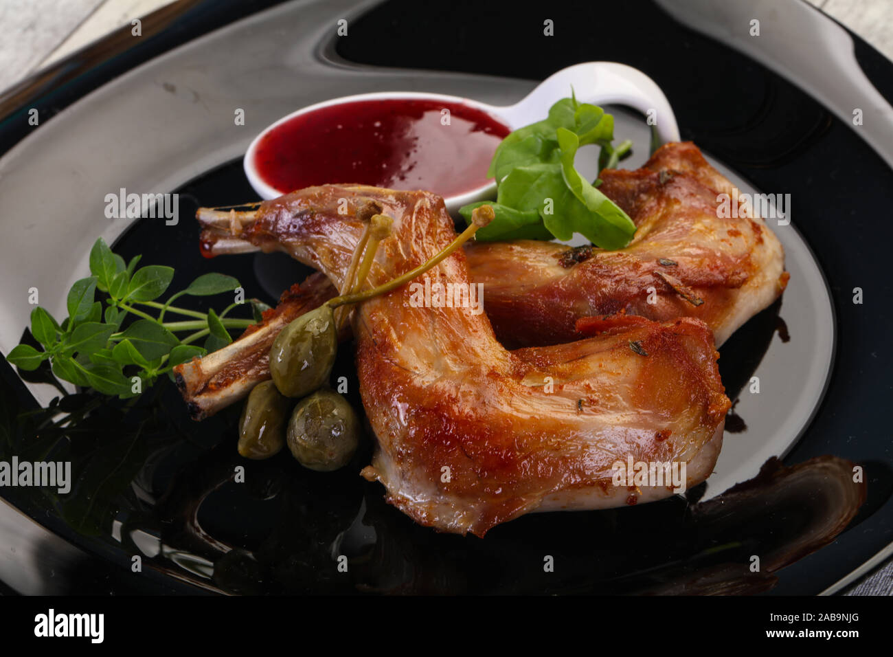 Roasted rabbit legs with cowberry sauce Stock Photo - Alamy