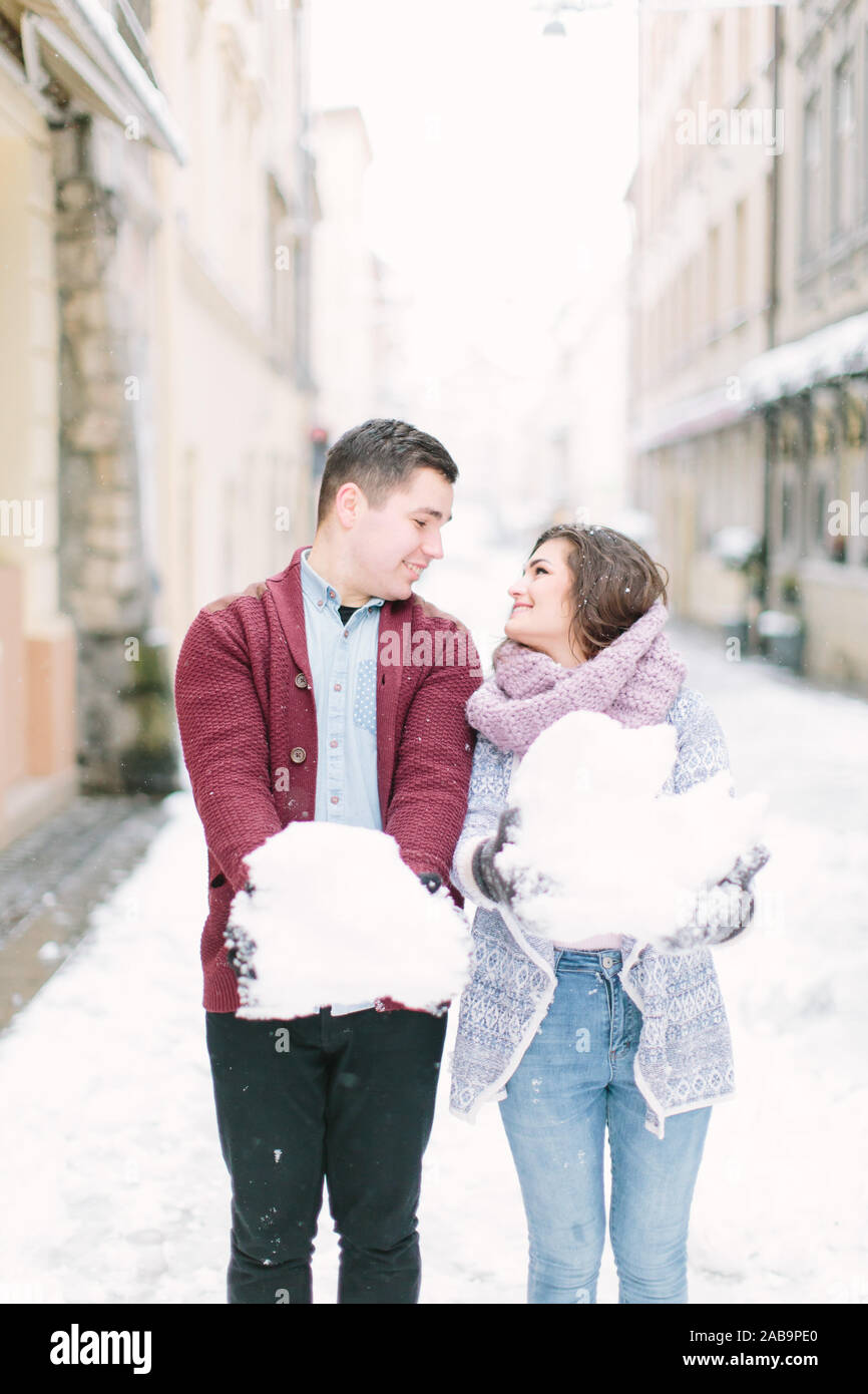 Young romantic couple kissing and having fun, holding big snowballs ...