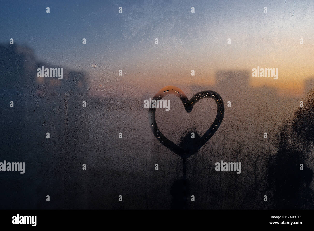 Heart shape drawn on moisturized glass window amid the dawn Stock Photo ...