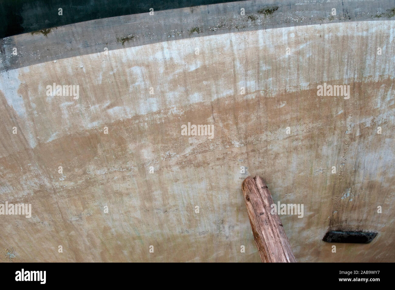 A Close Up Of The Stained Hull Of A Boat Supported By A Rustic Piece Of ...