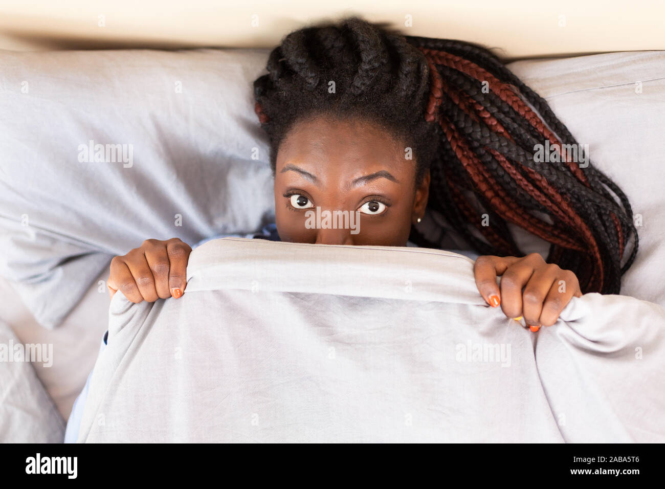 Afro Girl Peeking Out Of Blanket Lying In Bed, Top-View Stock Photo - Alamy