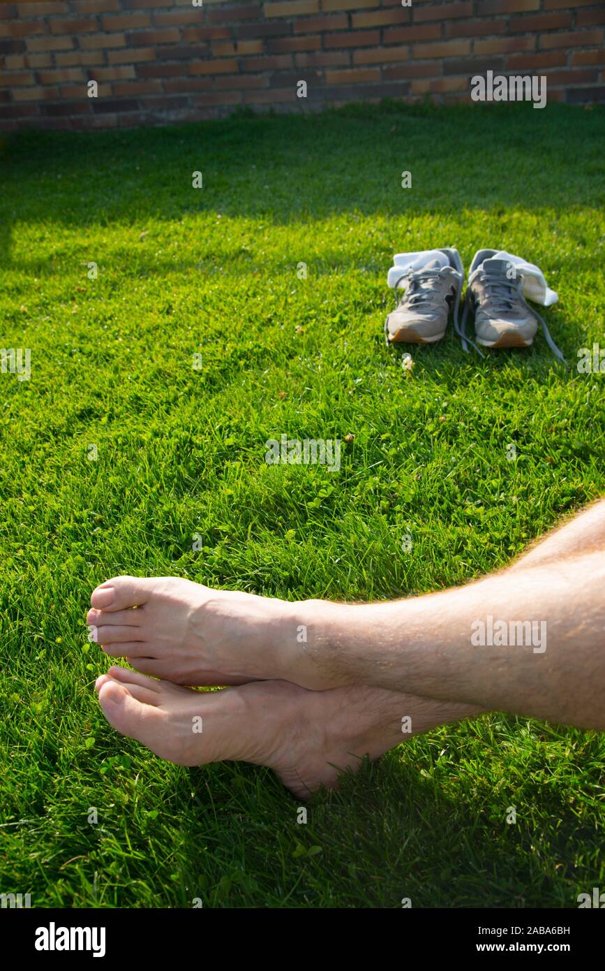 Barefoot man taking a rest on the grass Stock Photo - Alamy