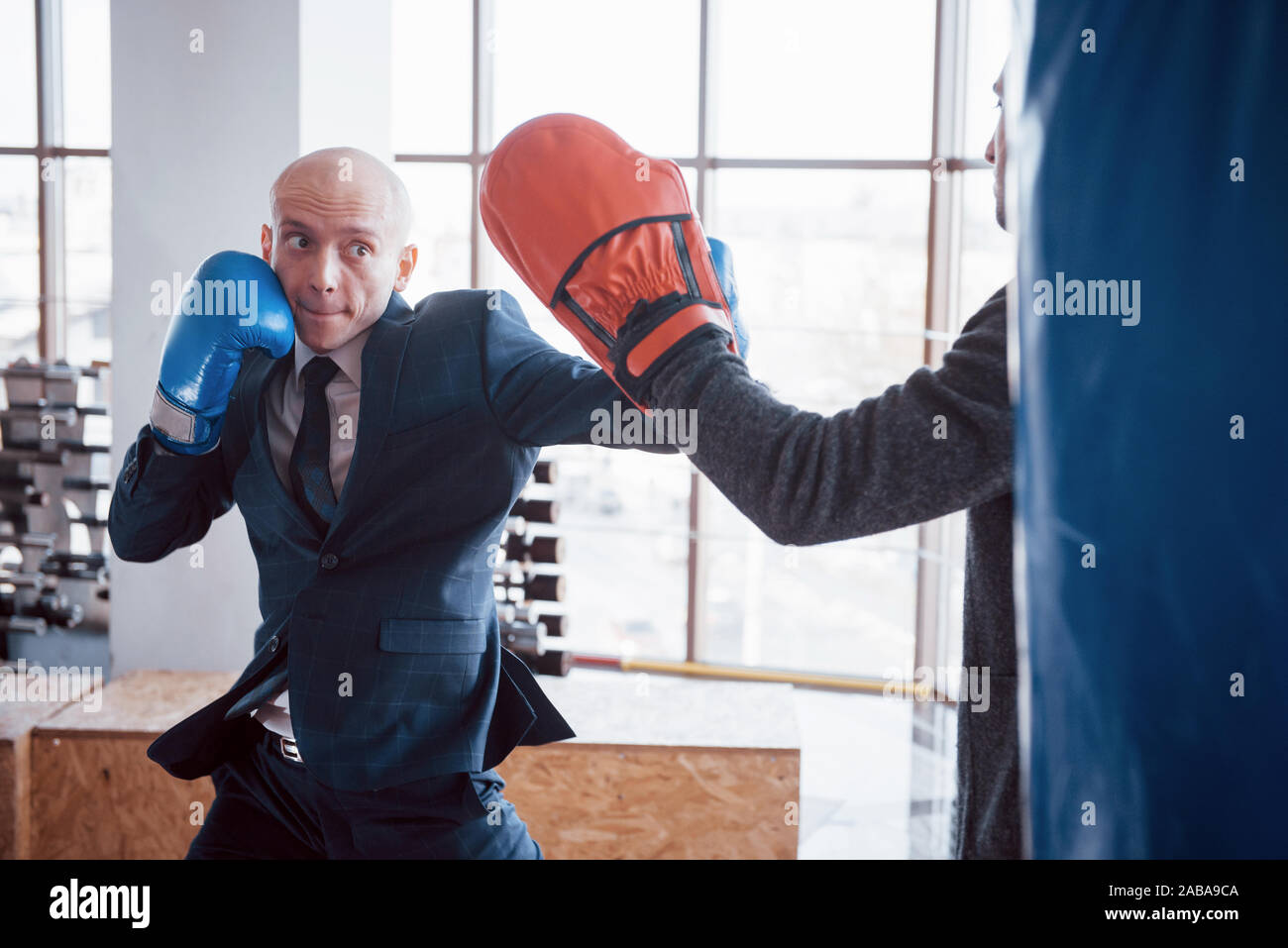 An angry bald businessman beats a boxing pear in the gym. concept of ...