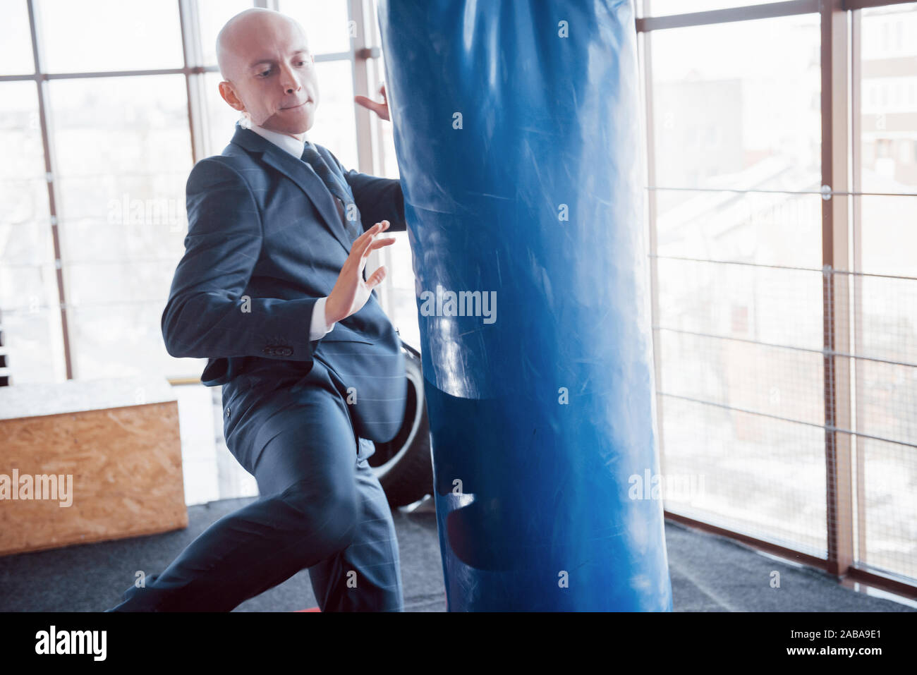 An angry bald businessman beats a boxing pear in the gym. concept of ...