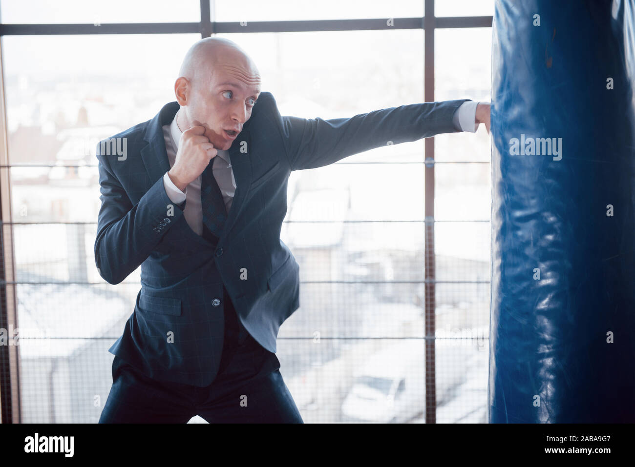 An angry bald businessman beats a boxing pear in the gym. concept of ...