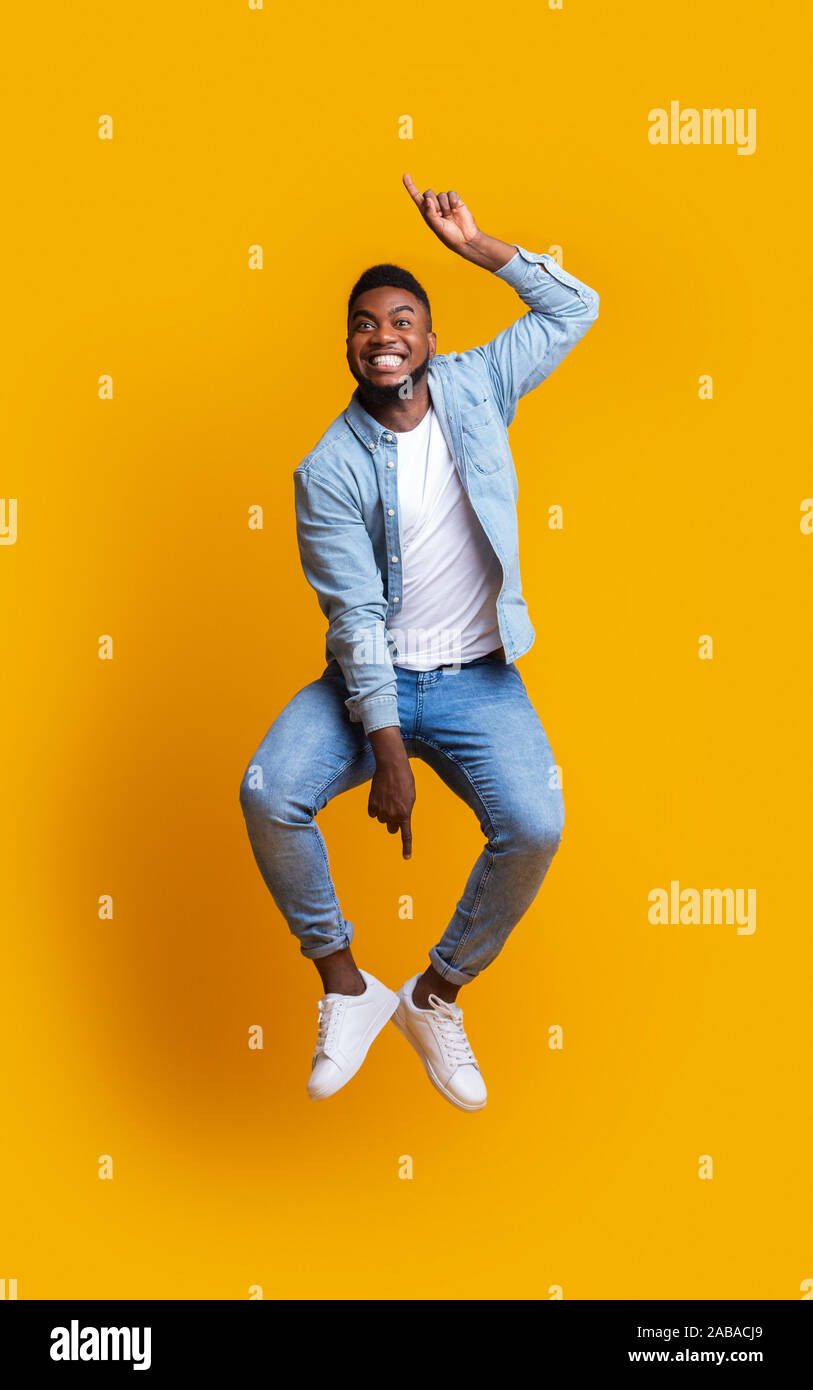 Black guy jumping in air, pointing up and down with hands Stock Photo ...