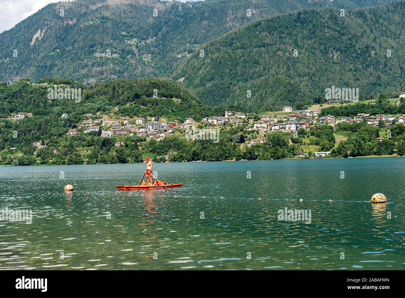 Lago di Caldonazzo, male lifeguard standing on an orange rescue rowing ...