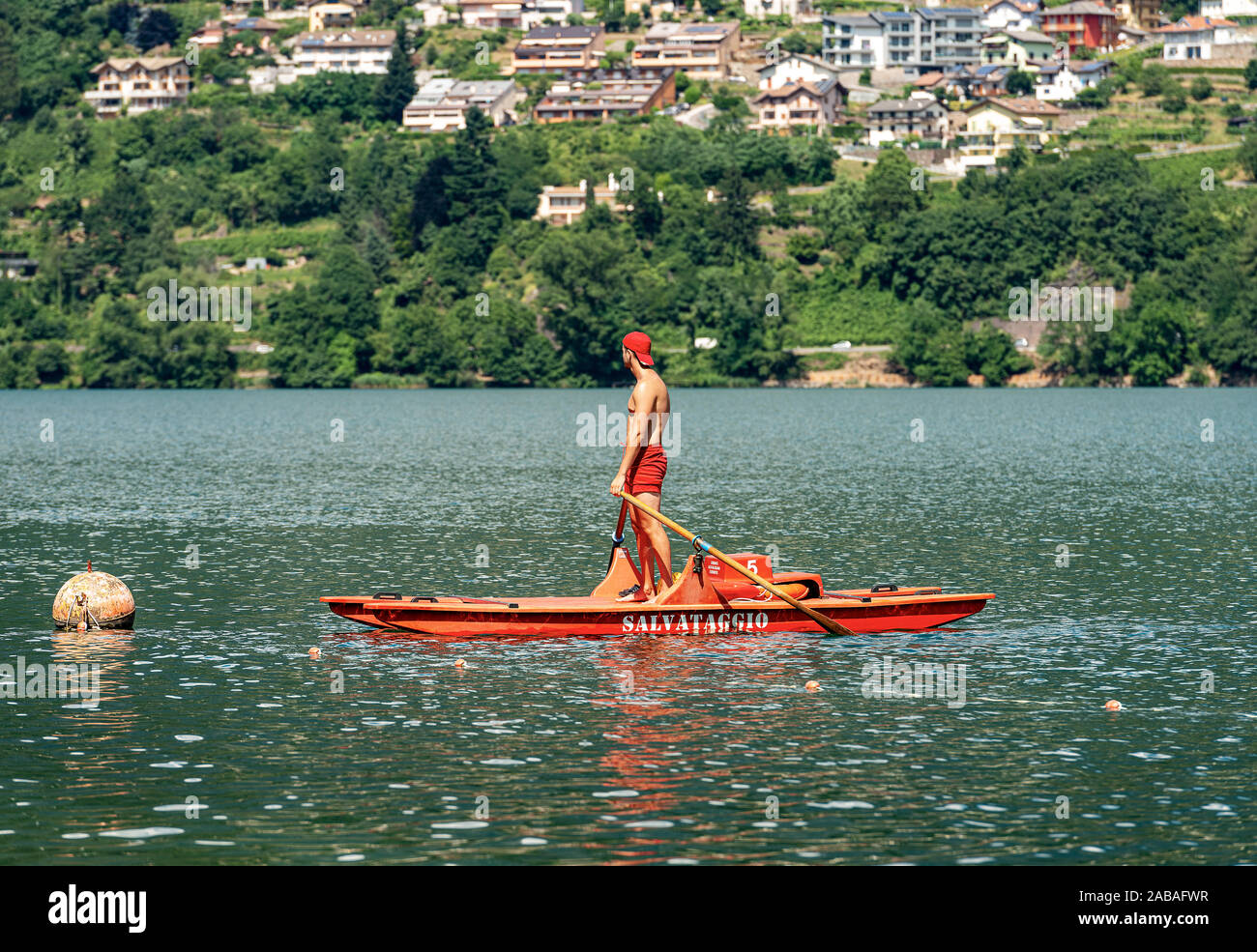 Lago di Caldonazzo, male lifeguard standing on an orange rescue rowing ...