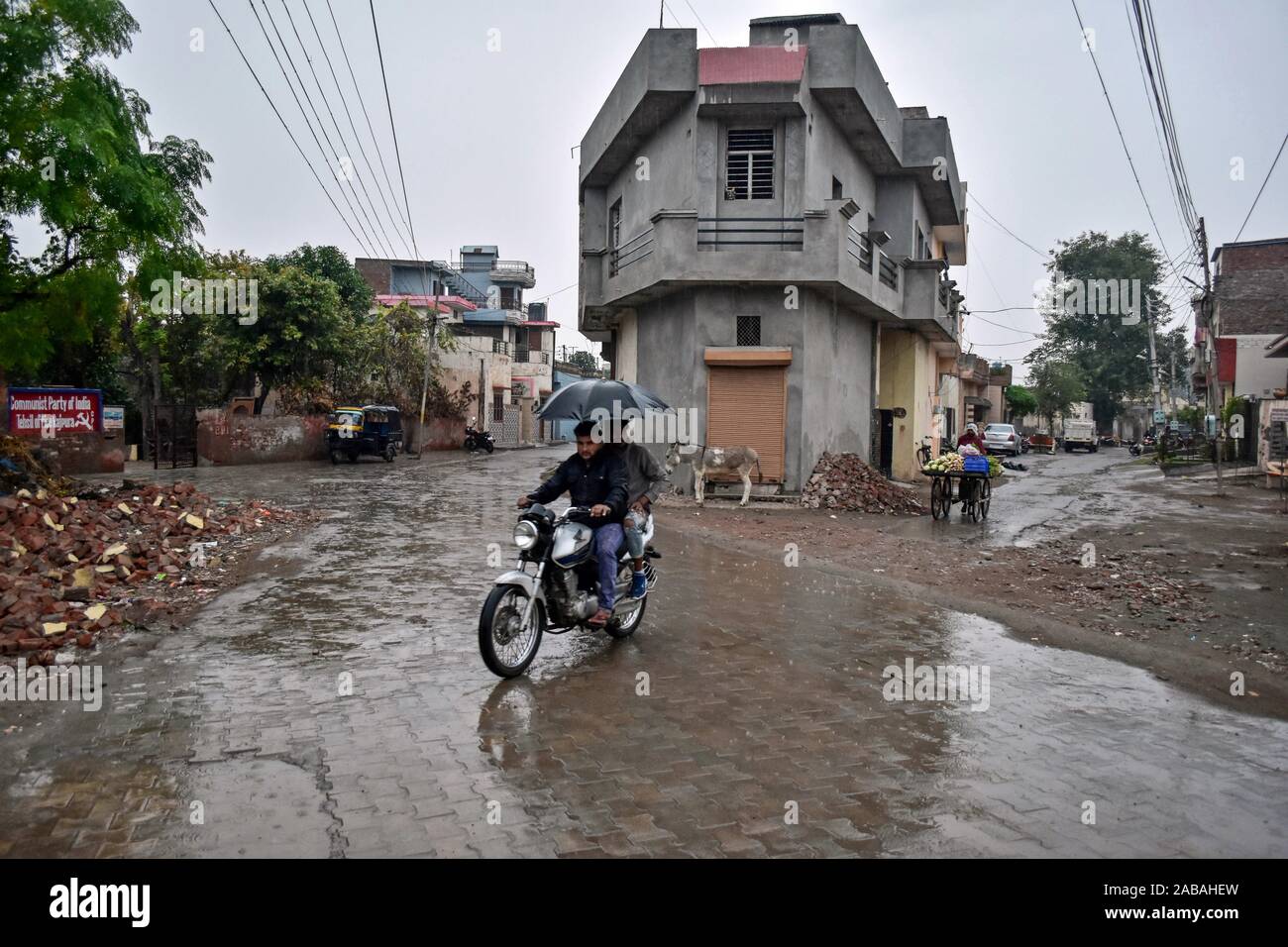 Men ride on a motorcycle during heavy rainfall in Rajpura town of ...