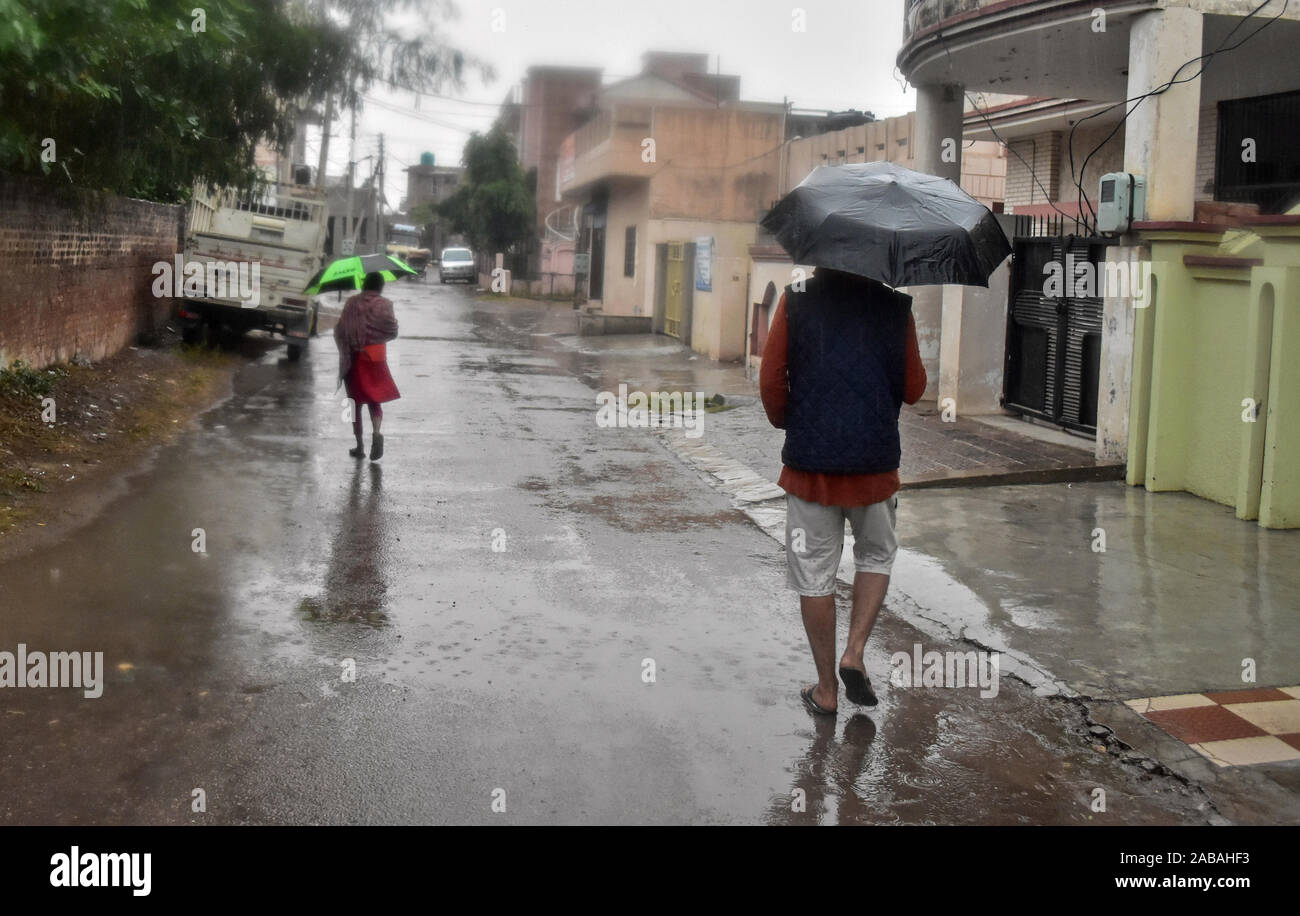 Residents walk along a road during heavy rainfall in Rajpura town of ...