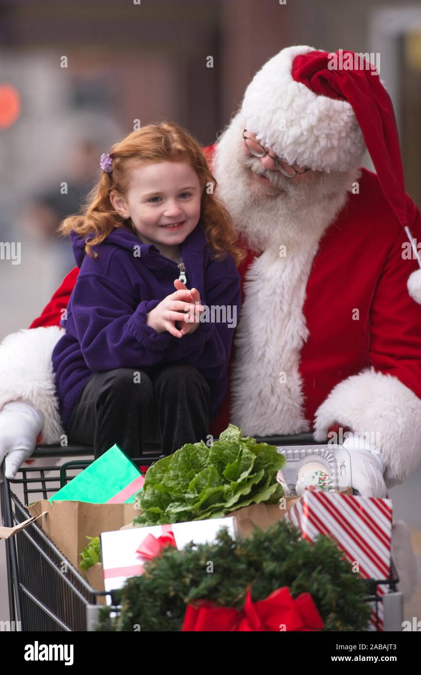 Santa with a little girl pushing a shopping cart full of presents and ...