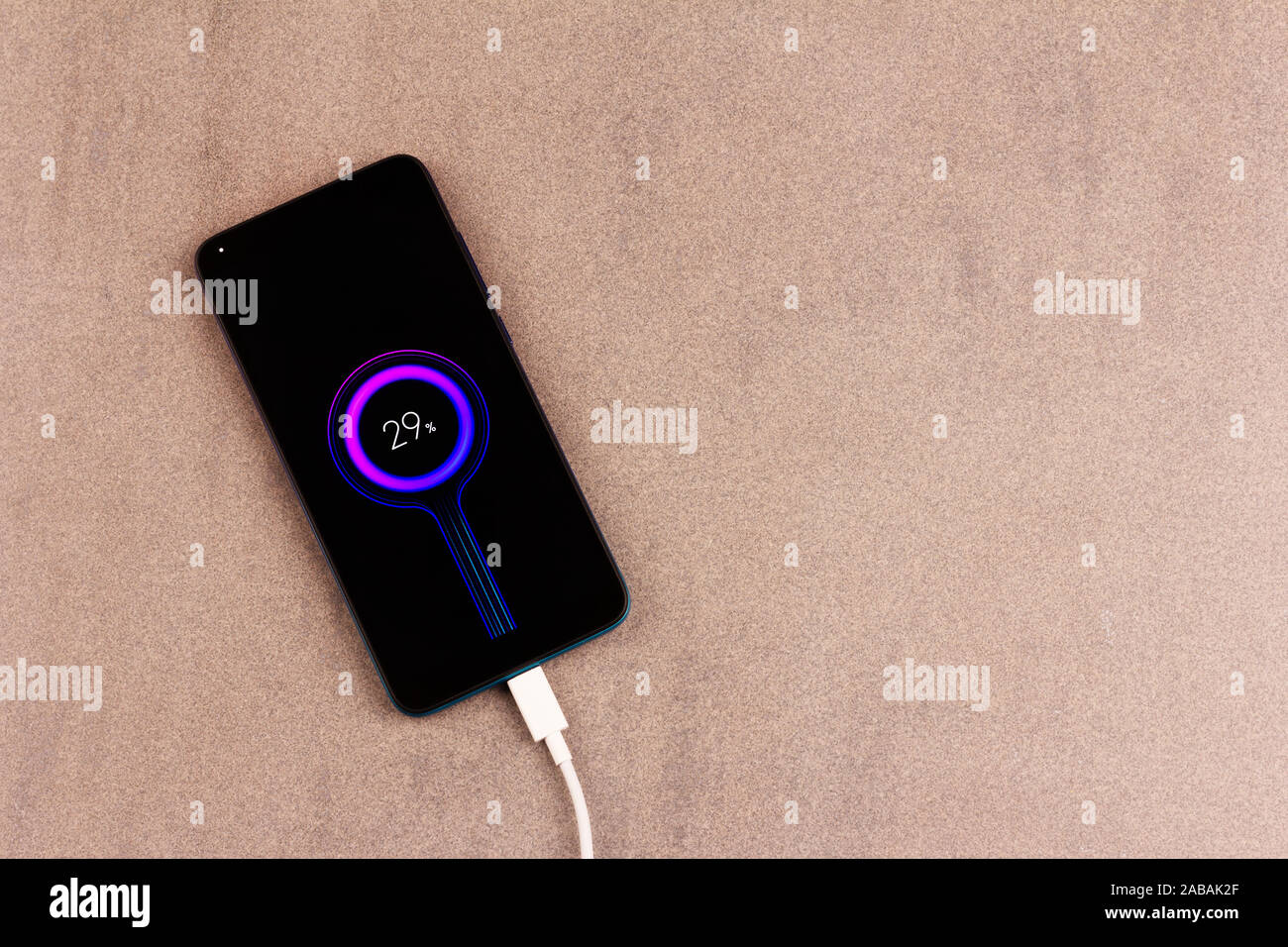 smartphone with battery indicator on screen with white charging wire on ...
