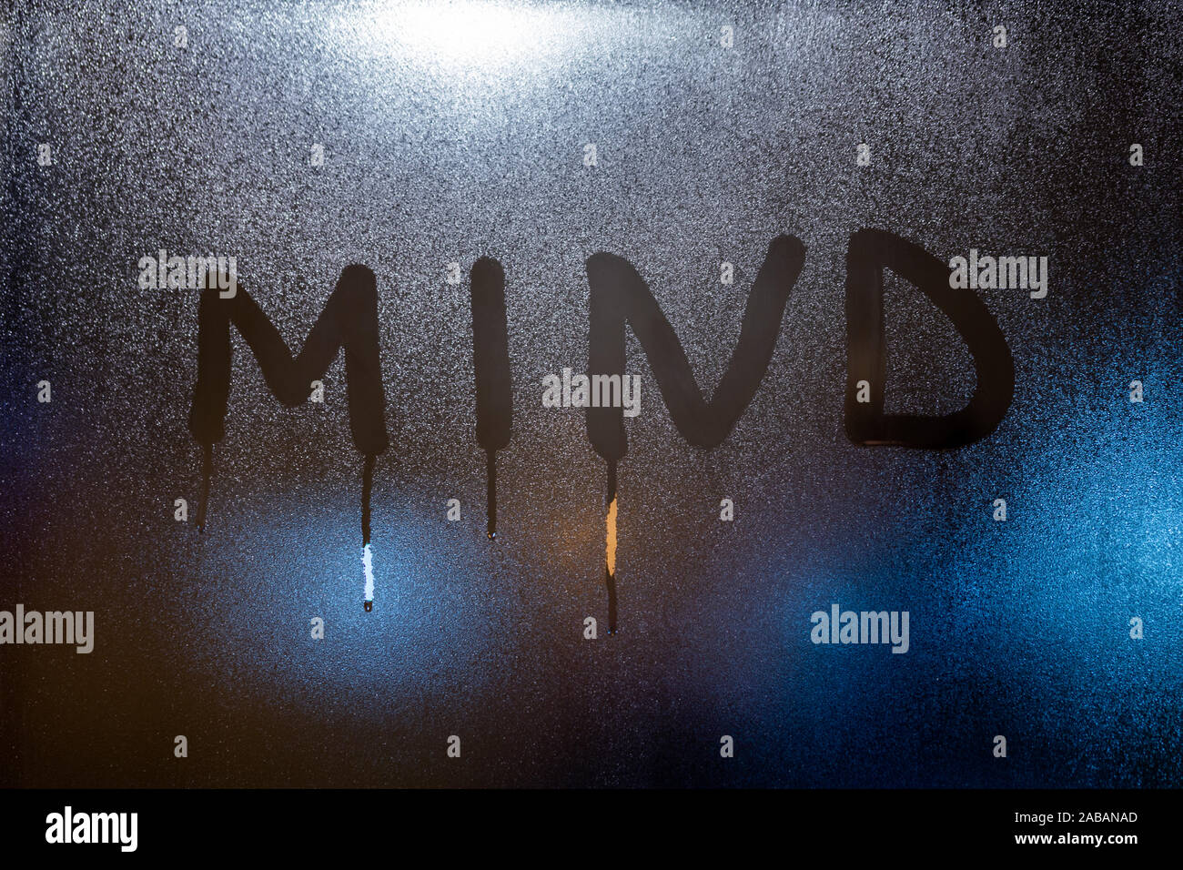 the word mind written on night wet window glass close-up with blurred ...