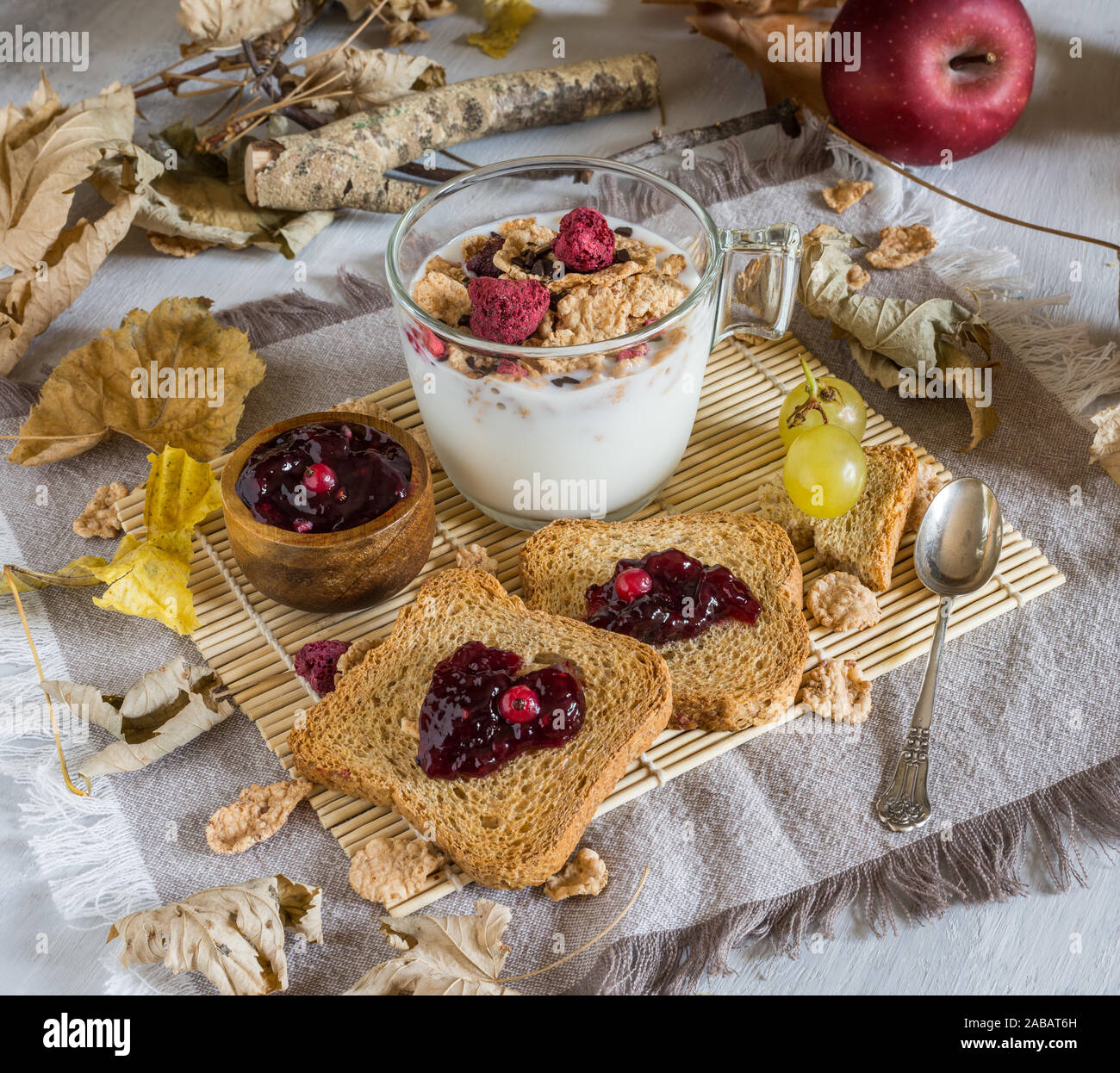 autumnal food background with milk, cereal, rusks and wildberries jam ...