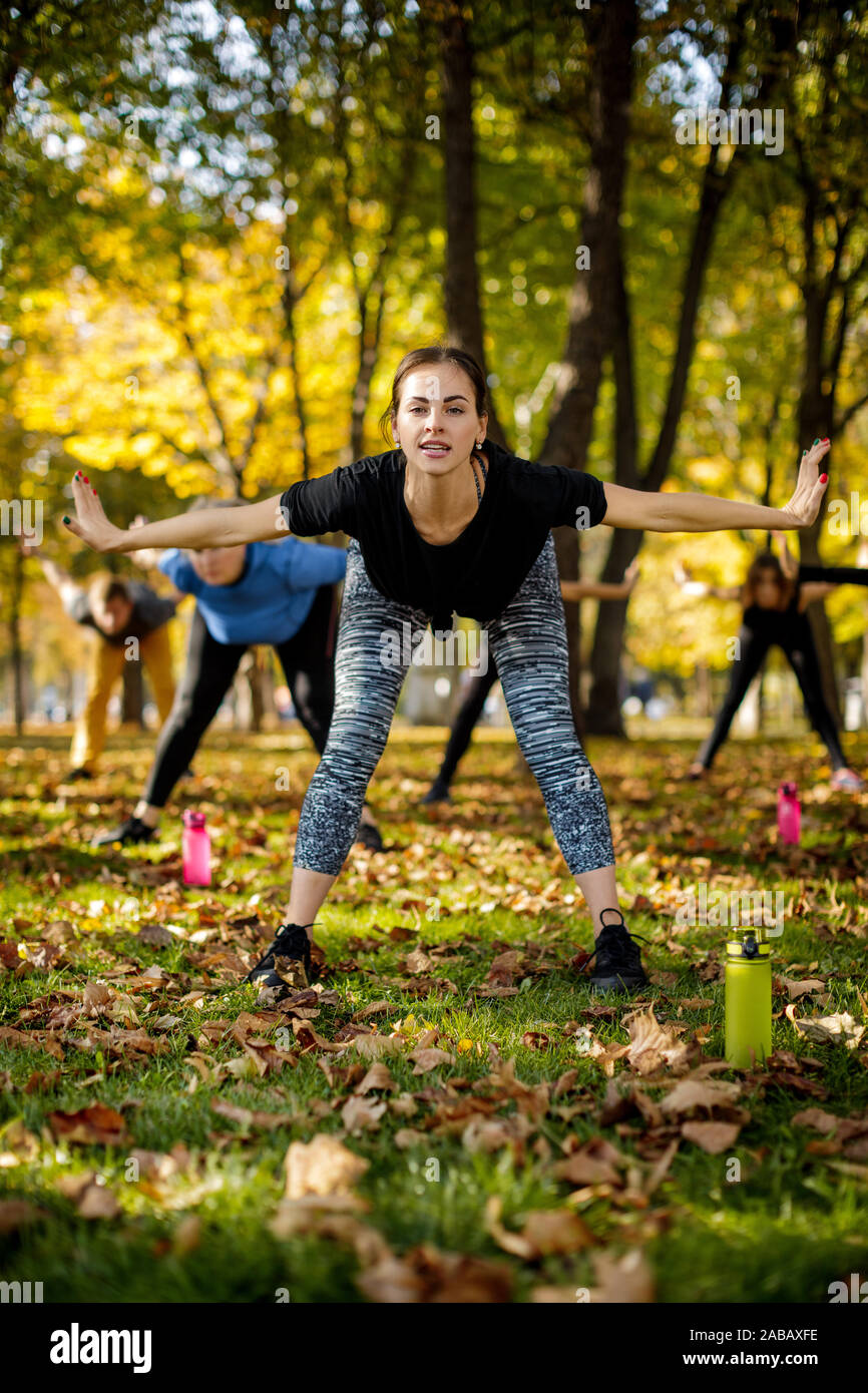 large group of people doing outdoor workout on green grass in park ...