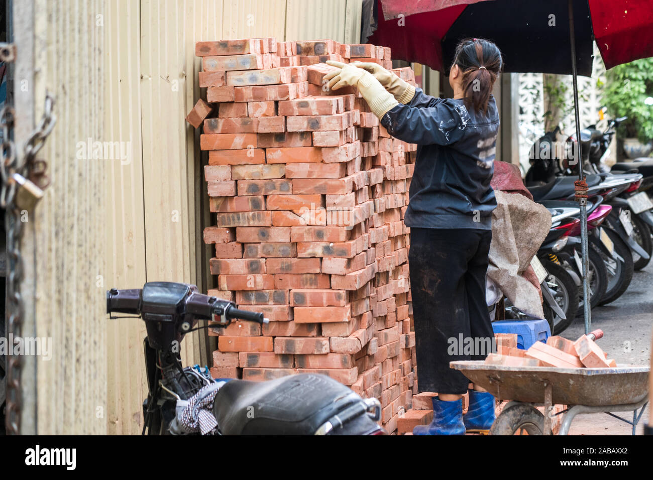 A asian woman piles bricks up on a construction site in Hanoi, Vietnam ...