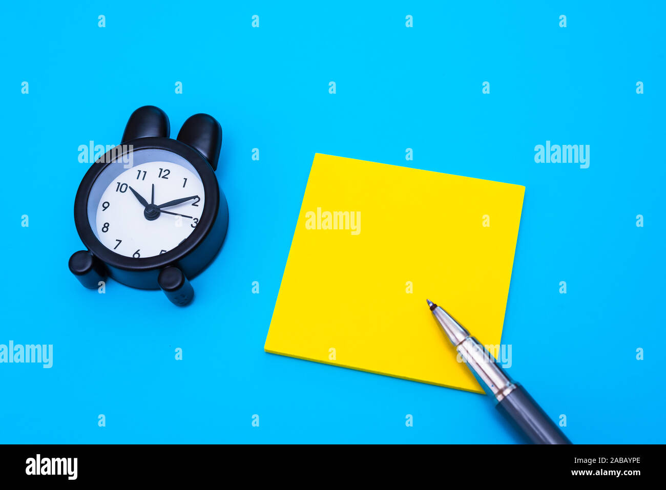 Flat lay of an alarm clock, pen and yellow paper to write any text ...