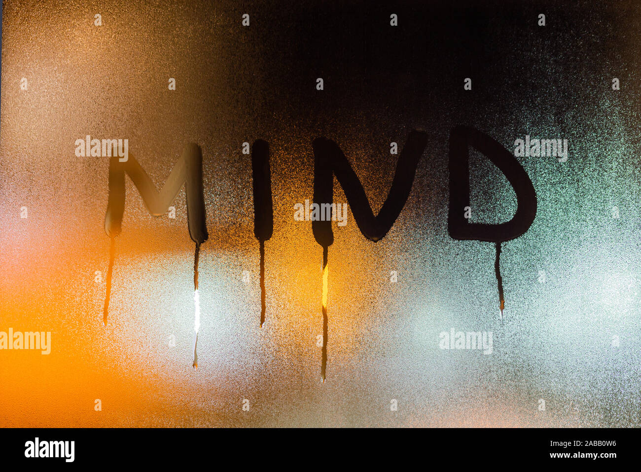 the word mind written on night wet window glass close-up with blurred ...
