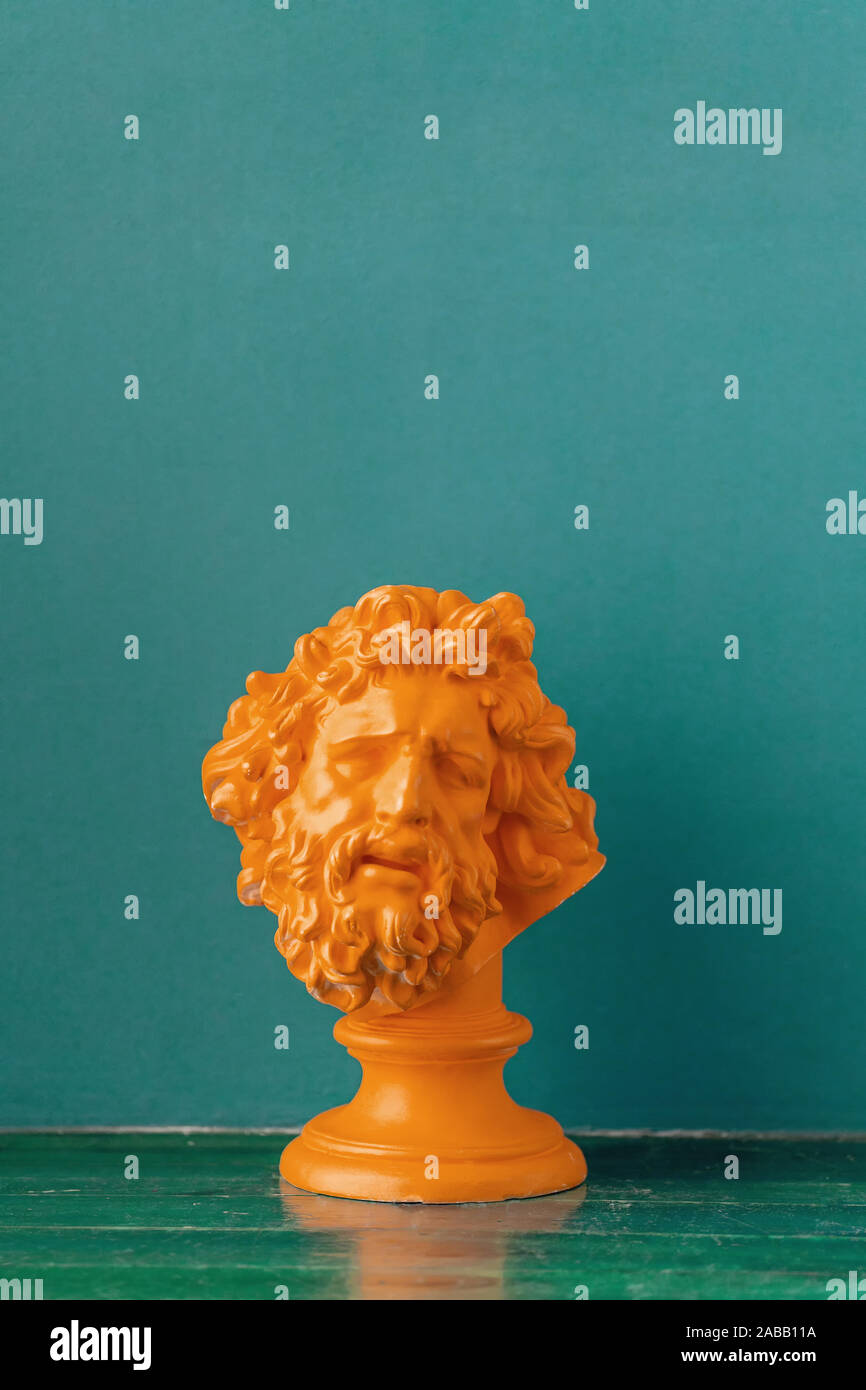 Color plaster head of ancient Greek sculpture on the floor against blue ...