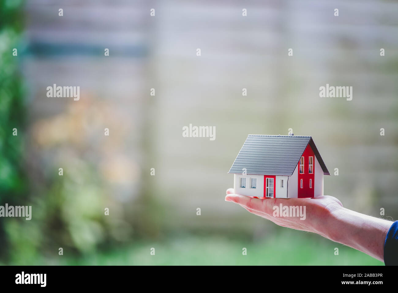 New home and house concept: Red house model outdoors in male hand, copy ...