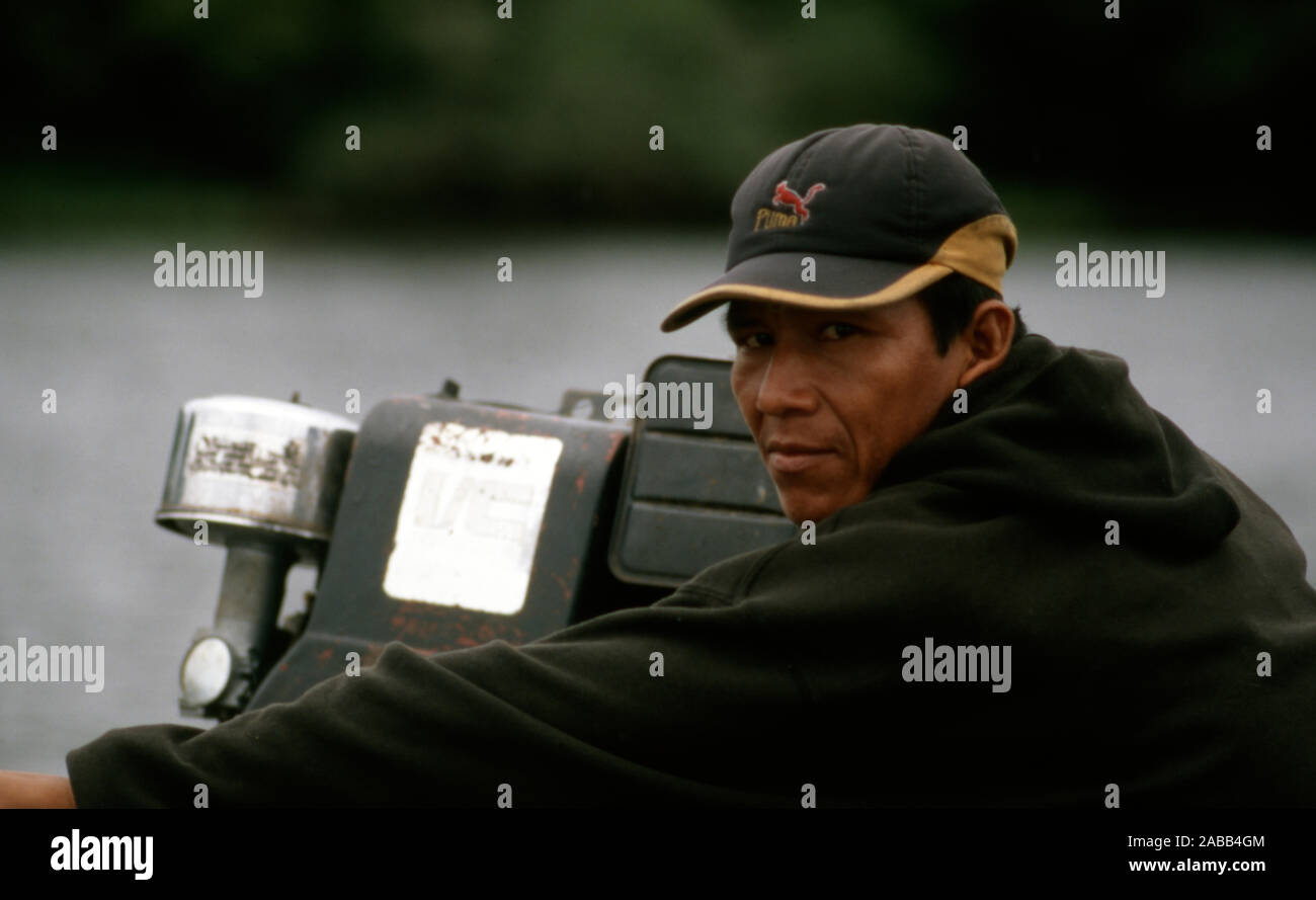 An indigenous Cocama man steers his small boat up an Amazonian river ...
