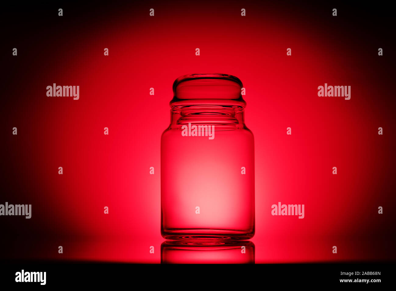Empty glass jar on a red and black background Stock Photo - Alamy