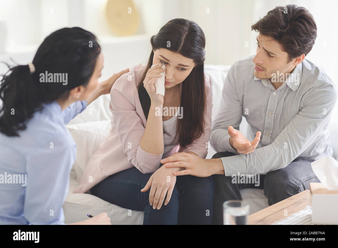 Psychotherapist And Young Man Supporting Upset Woman During Therapy