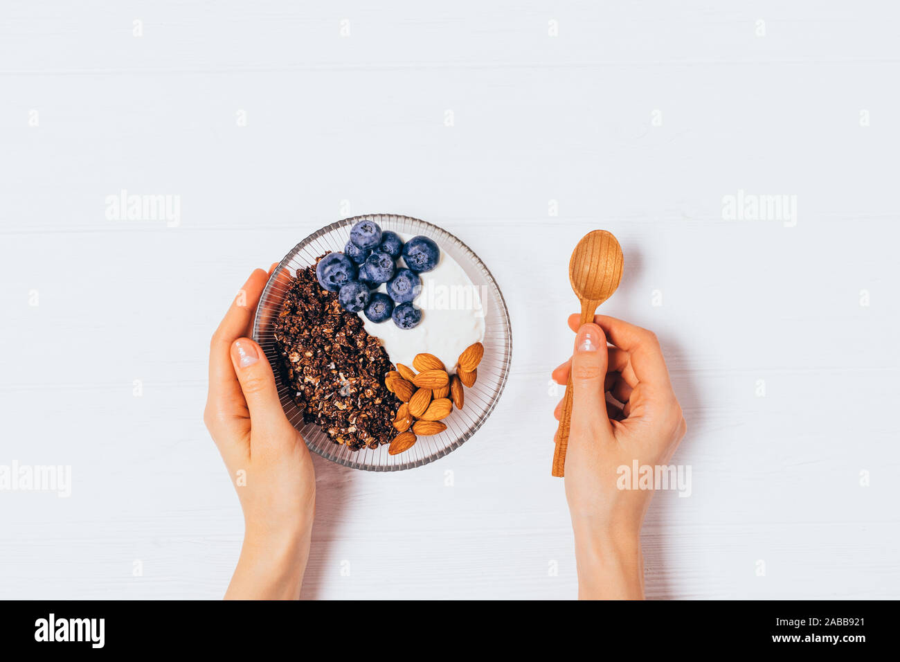 Female hands holding bowl of homemade granola with yogurt, blueberries ...