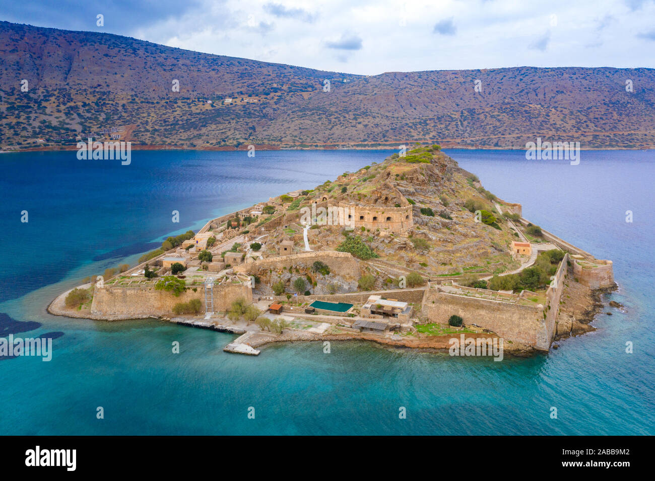 Aerial view of the island of Spinalonga with calm sea. Here were ...