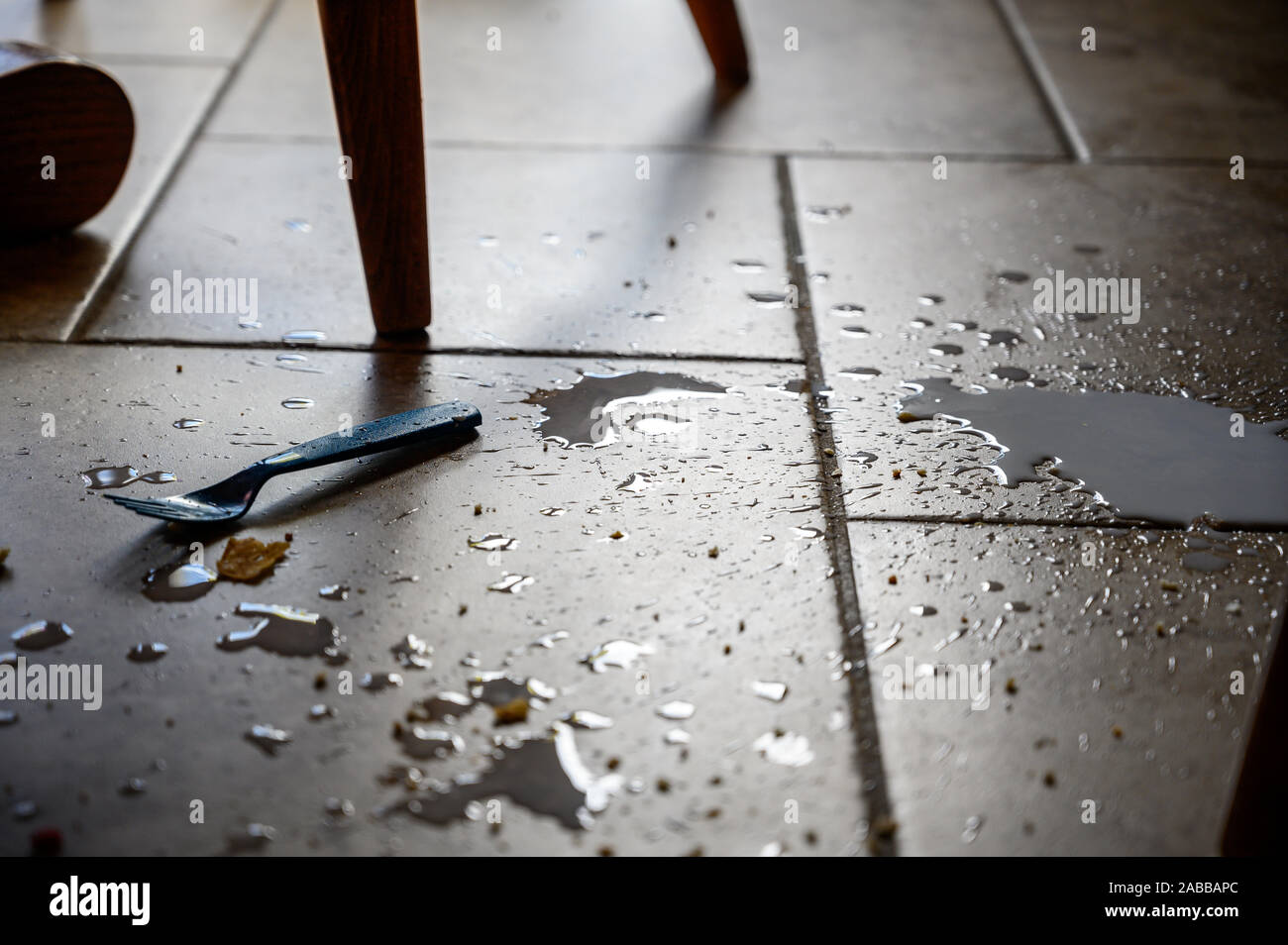 kitchen table with spilled milk, crumbs, and a plastic fork on a brown ...