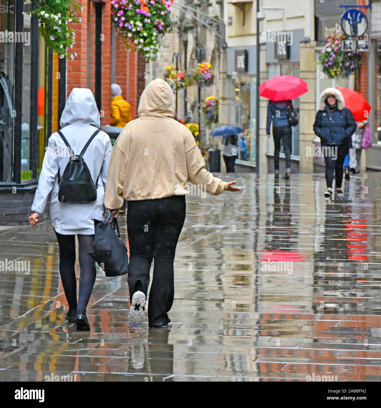 Street scene raining on people in wet weather town centre pedestrians ...