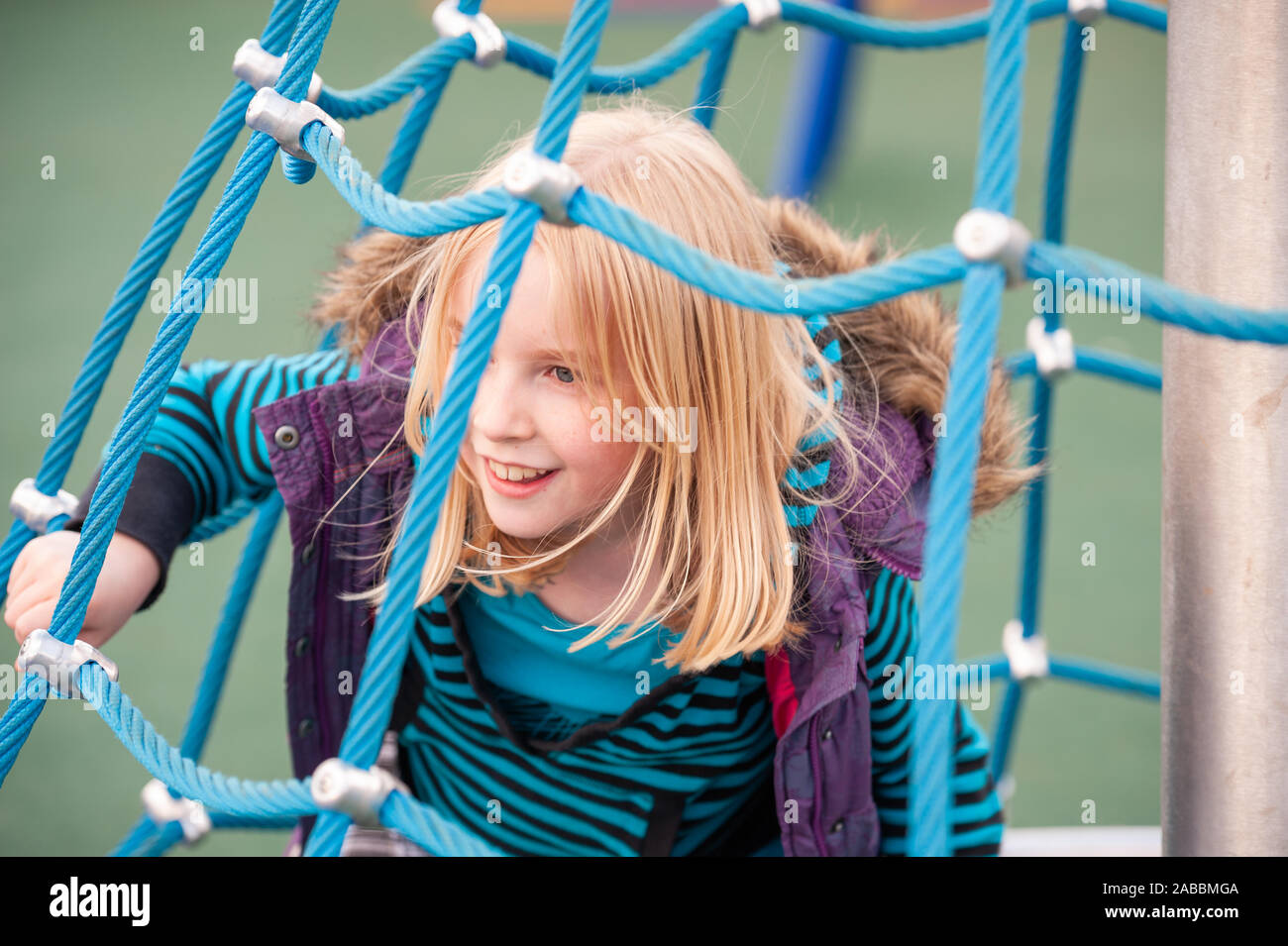 Pretty young blonde girl playing on a rope climbing frame Stock Photo ...