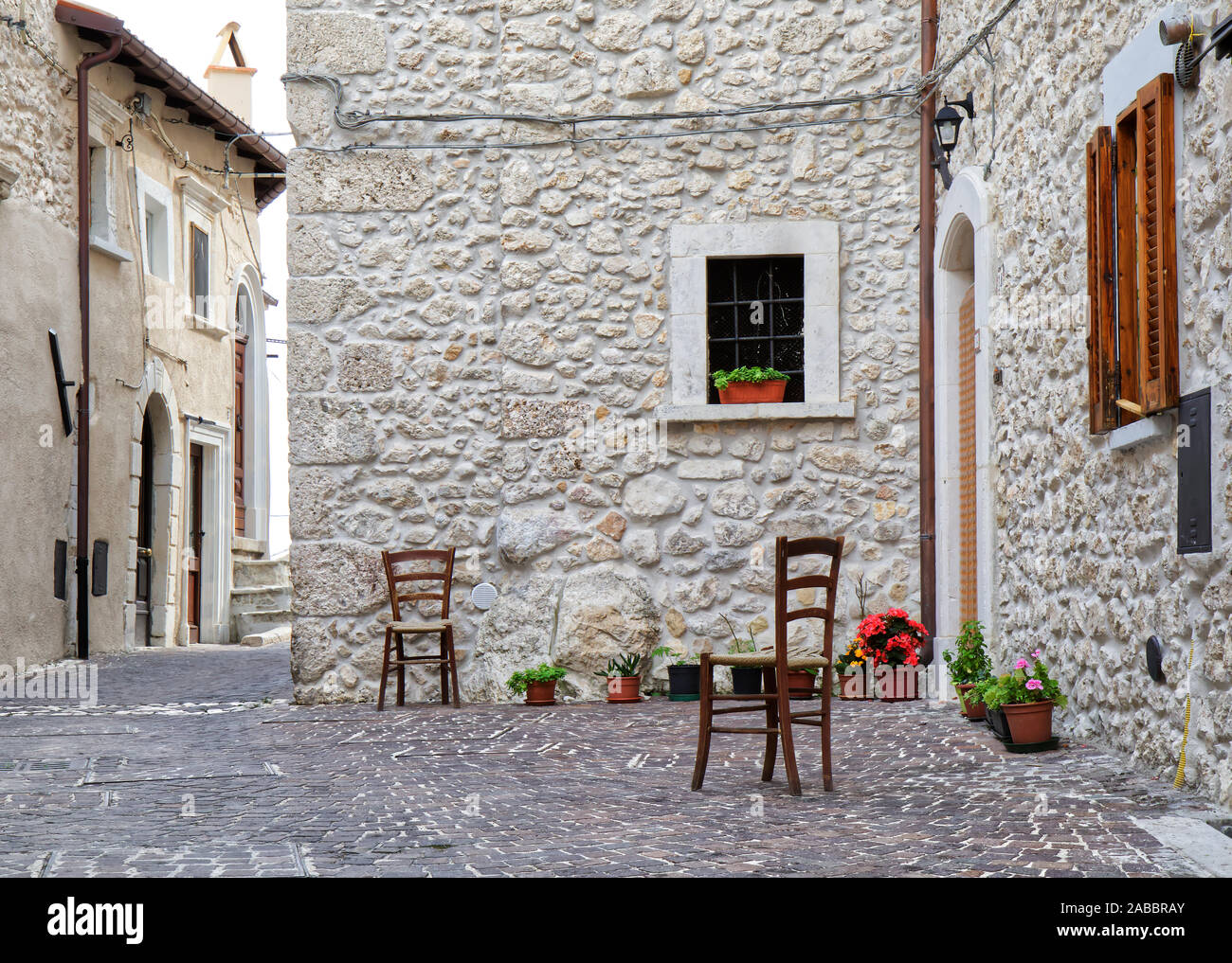 Little square in an old village with two empty chairs in front of a ...
