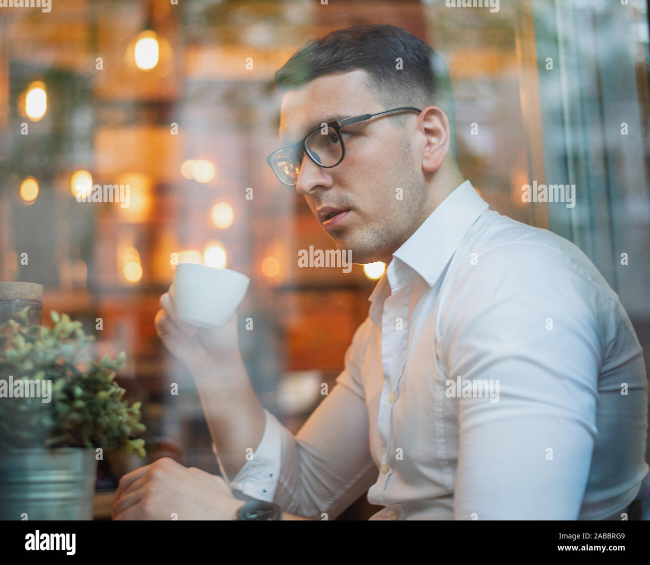 Intelligent young man drinking coffee Stock Photo - Alamy