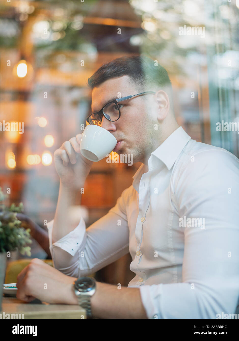 Intelligent young man drinking coffee Stock Photo - Alamy