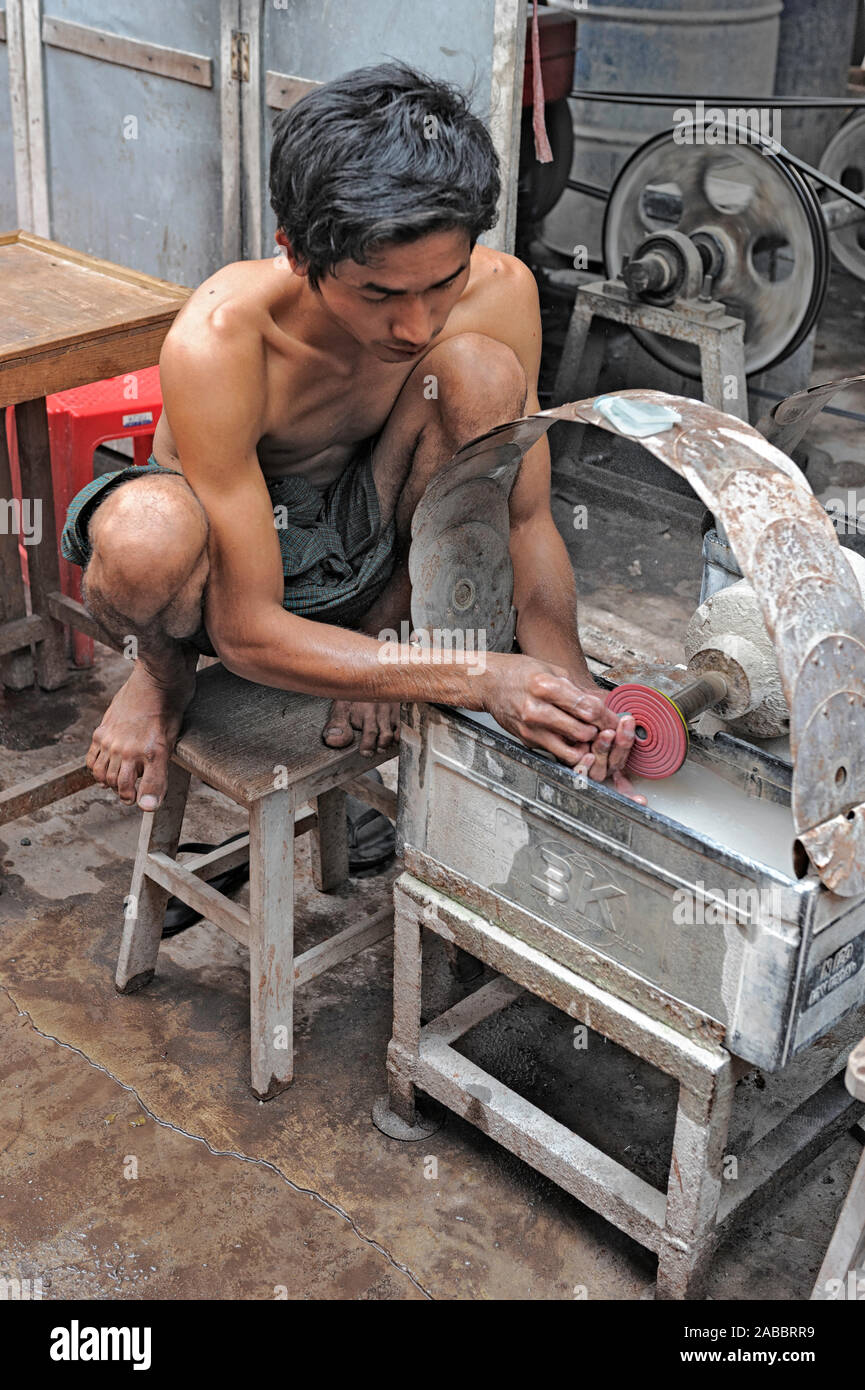 Man polishing small jade stones to be used in jewelry Mandalay Myanmar ...