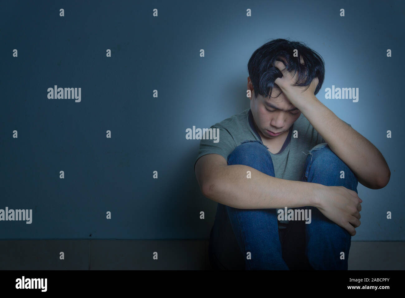 sad man hug his knee and cry sitting alone in a dark room. Depression ...
